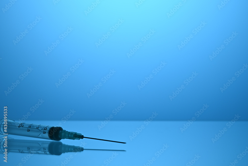Plastic medical syringe with metal needle. Inoculation syringe on light ...