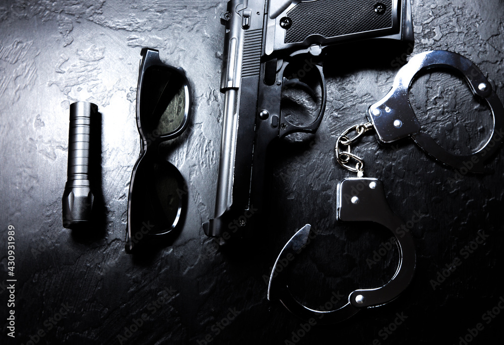 Black gun, flashlight, glasses and Police metal real handcuffs lie on ...