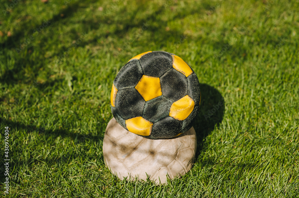 Two deflated old football balls lie on the green grass of the sports ...