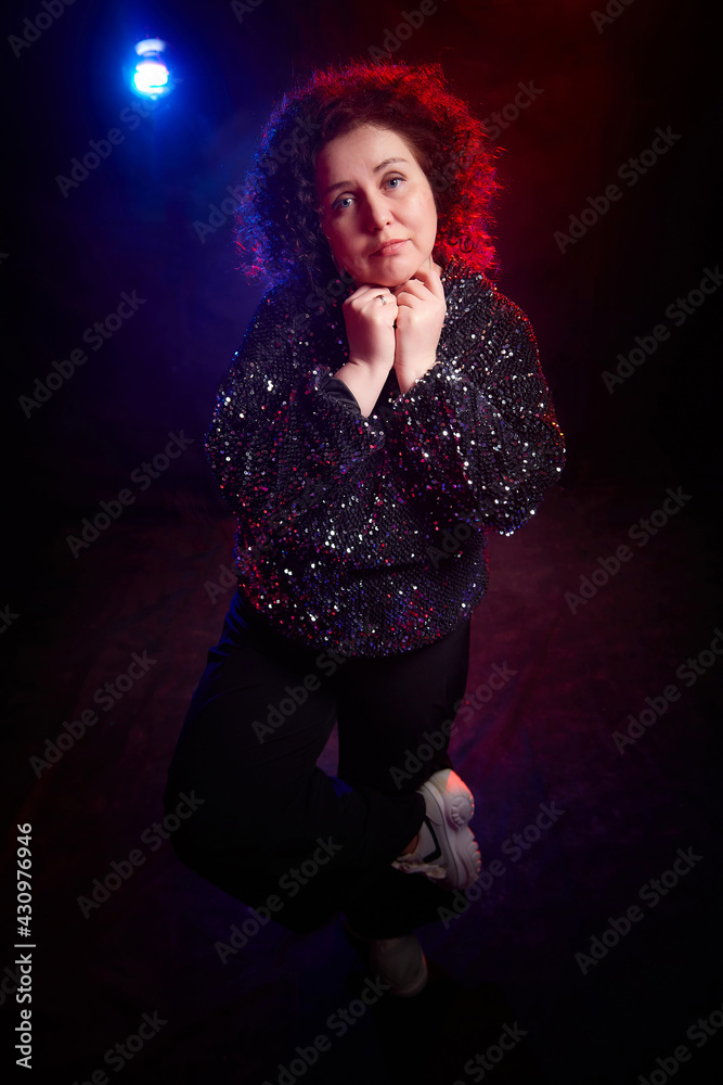 A brunette curly girl in black shiny clothes looking as teen bully on a ...