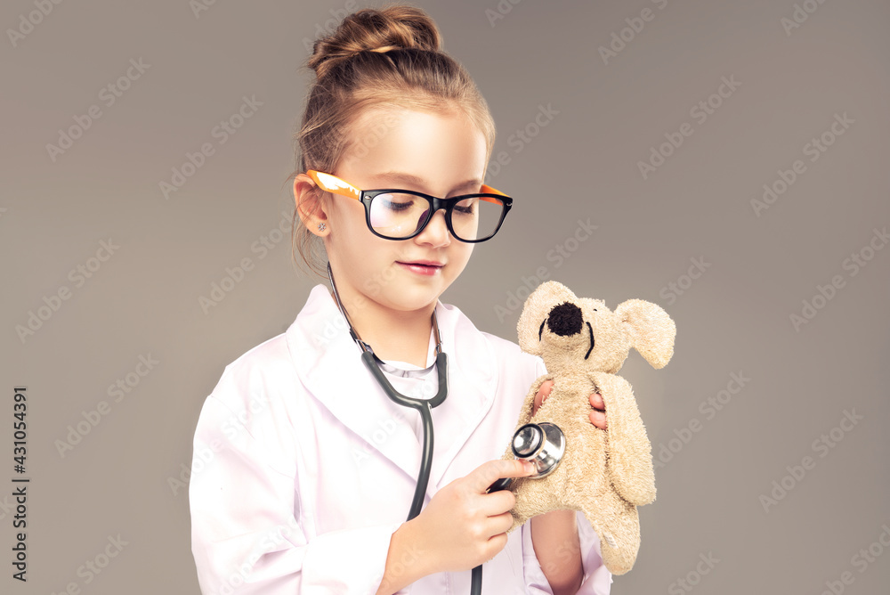Child girl in a medical gown and stethoscope plays and pretends to be a ...