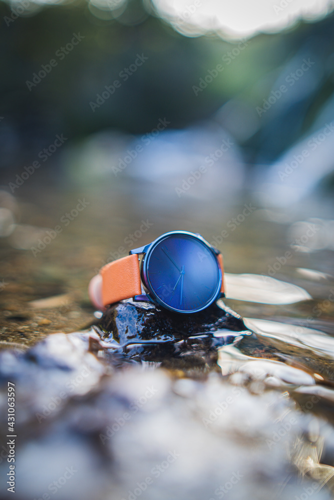 Reloj azul violeta con malla de cuero sobre roca en el medio del agua ...