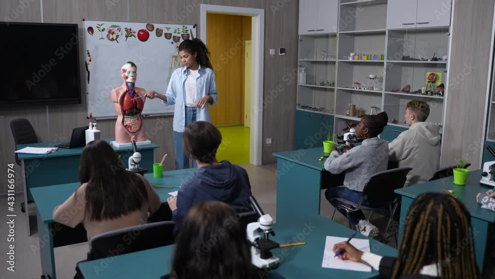 Multinational high school students listening to female teacher ...
