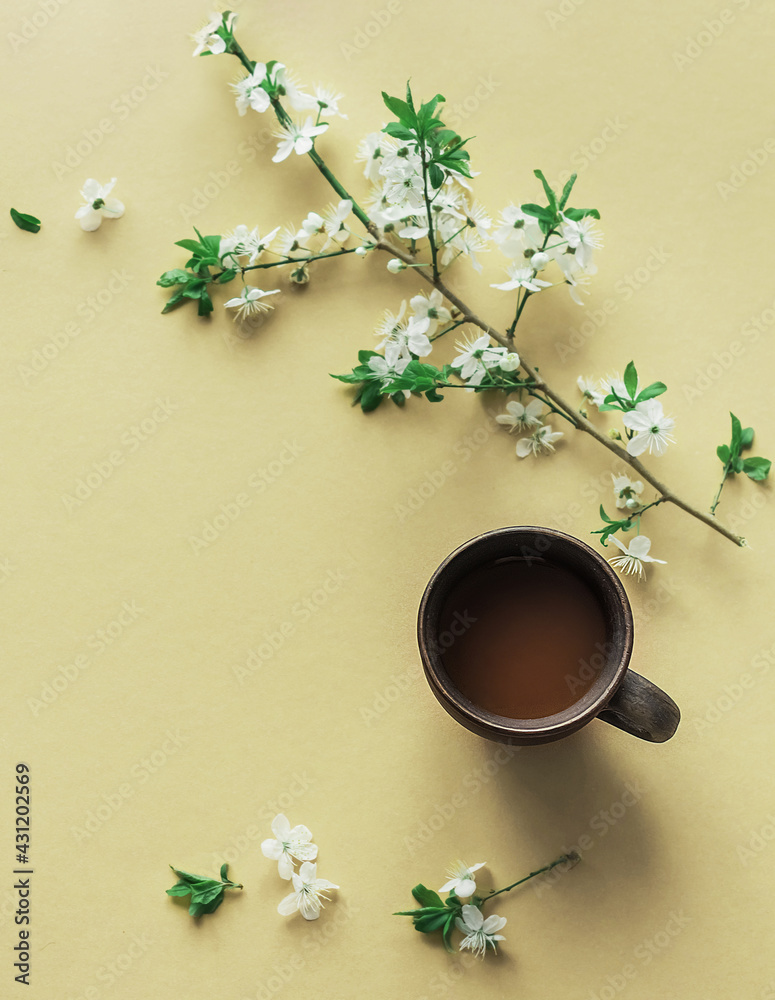 A cup of hot morning coffee and spring blooming branches on a yellow ...
