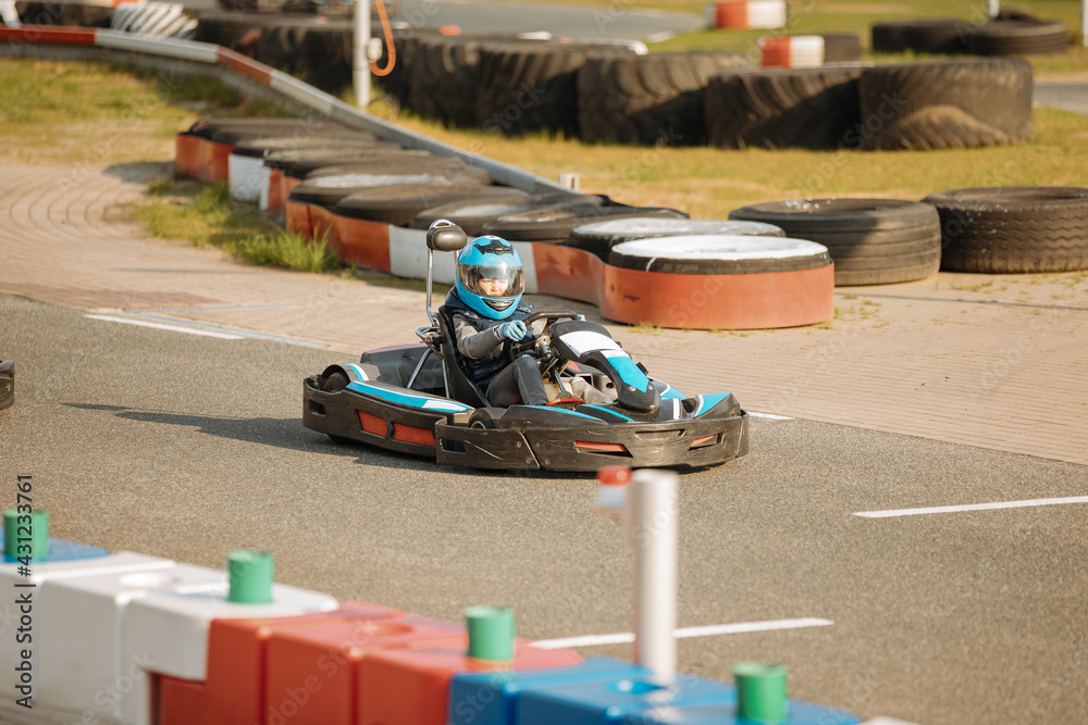 six year old boy drives go-kart. Small child drives kart on a racetrack ...