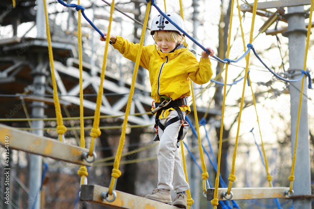 Little boy having fun in Adventure Park for children amoung ropes ...