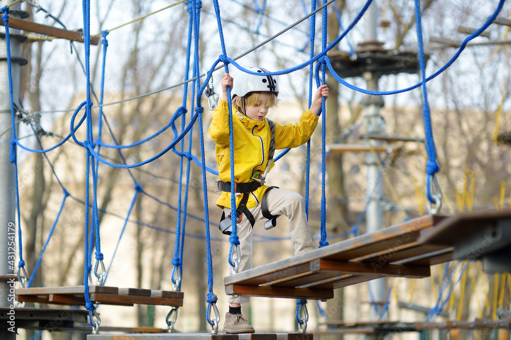 Little boy having fun in Adventure Park for children amoung ropes ...