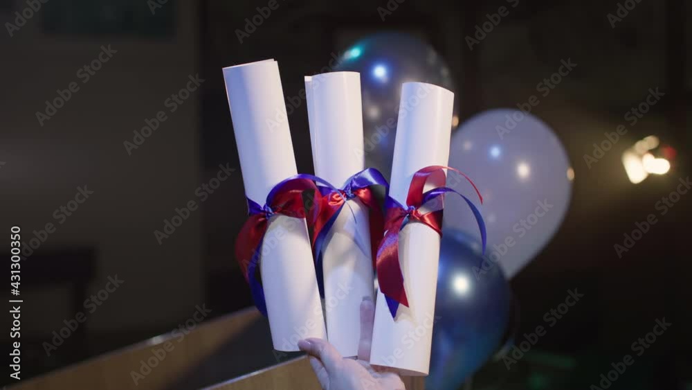 certificate of graduation tied with red and blue ribbon in hand ...