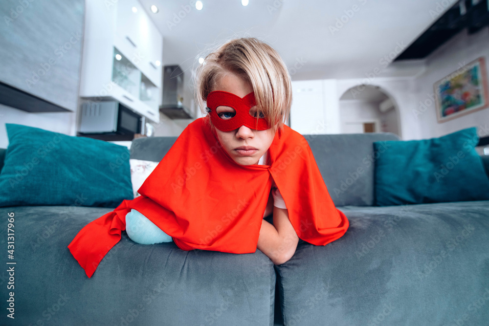 Superhero child sitting on sofa at home - Portrait of a kid in a ...