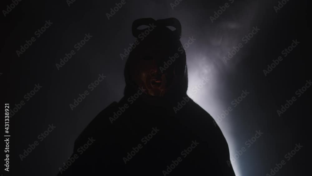 Creepy, masked cultist standing in a dark room. Scary horror scene ...