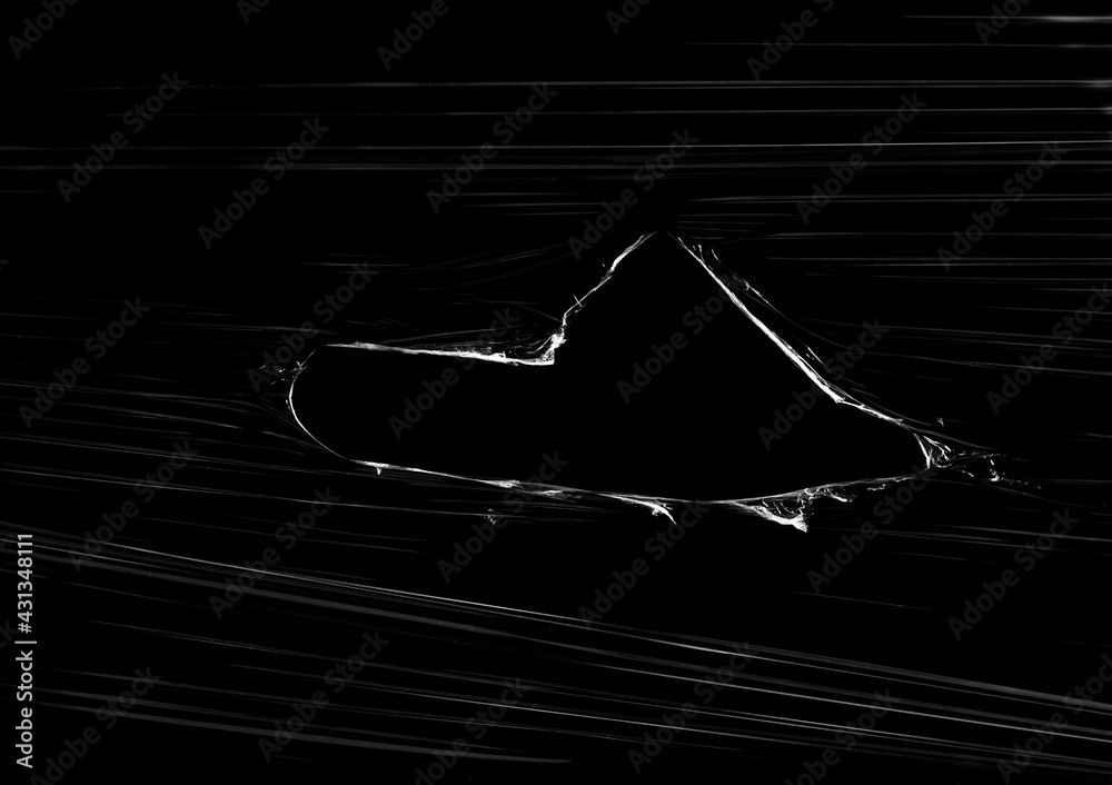 a transparent plastic wrap with a hole on black background. realistic ...