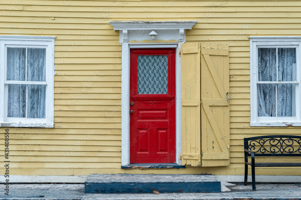 The exterior wall of a yellow wood clapboard heritage house. The door ...