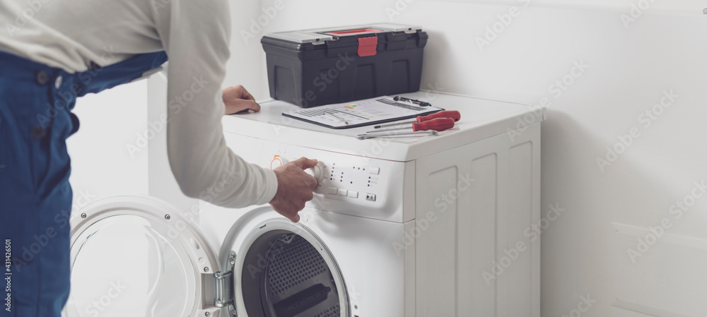 Professional repairman fixing a washing machine Stock Photo | Adobe Stock