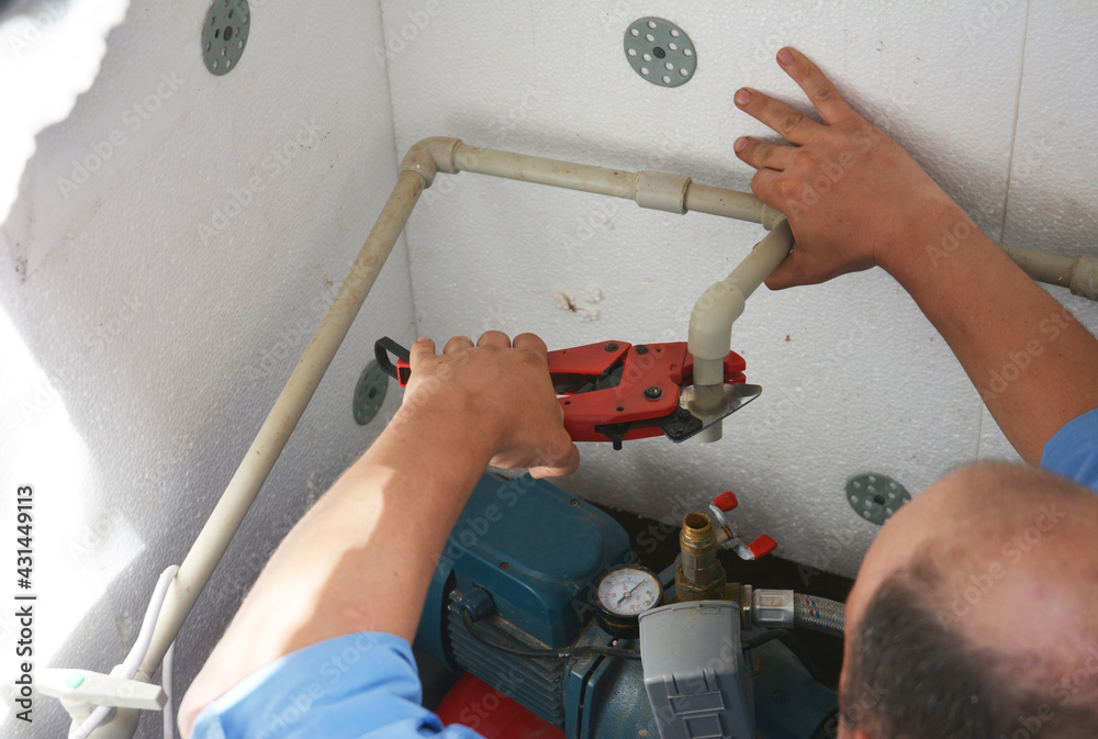Borehole water pump station installation. A man is connecting water ...