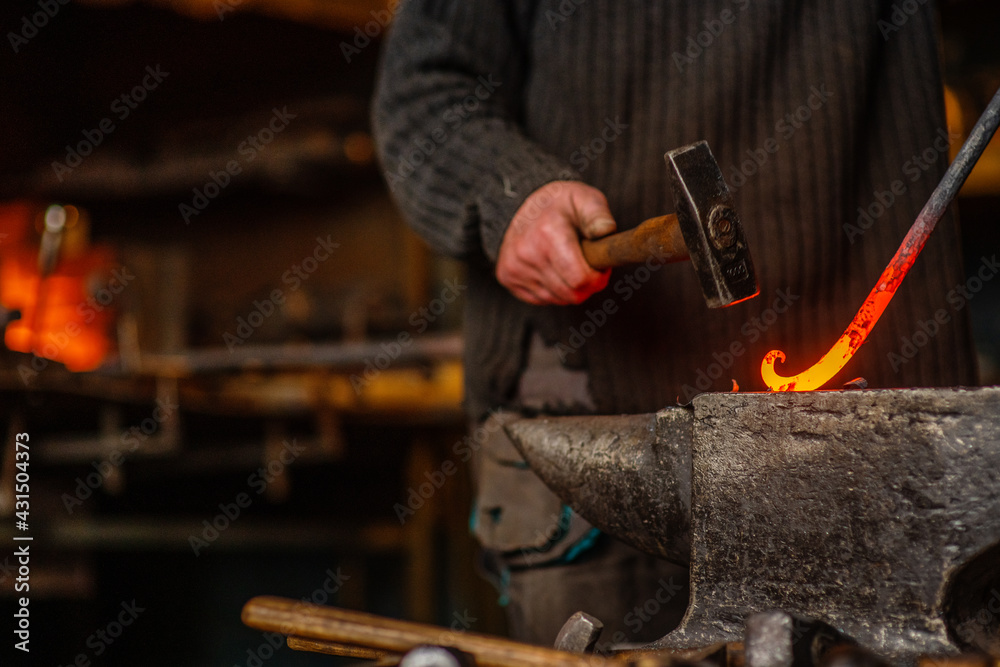 The blacksmith twists the spiral with a sledgehammer, placing a red-hot ...