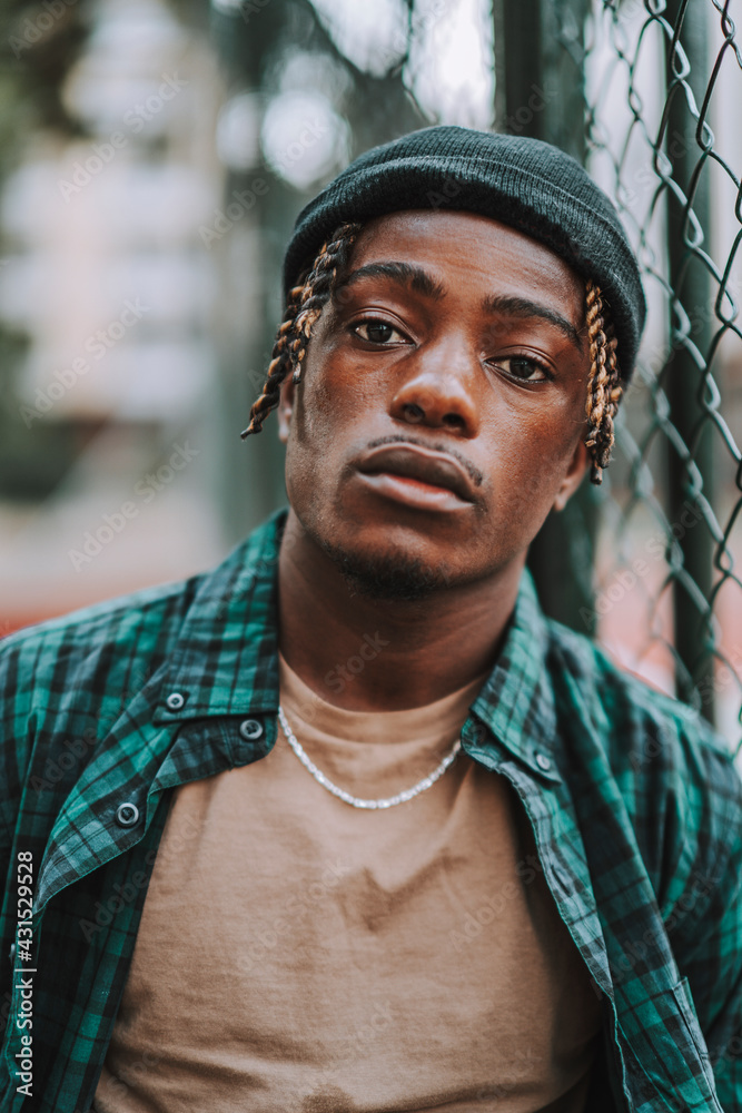 Chico negro joven y guapo posando junto a una cancha de baloncesto ...