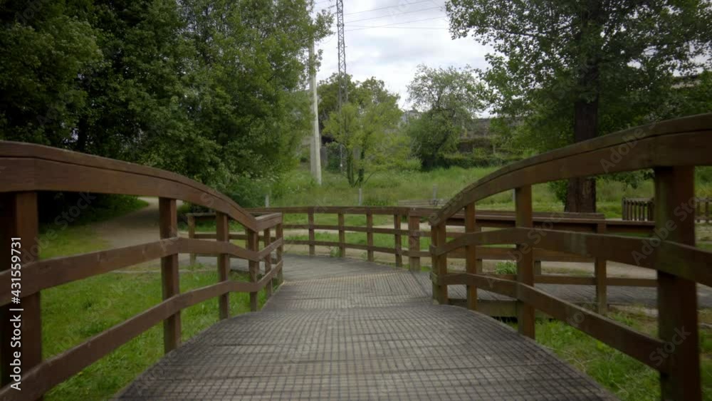 brown wooden bridge in the middle of nature on a path to cross a river ...