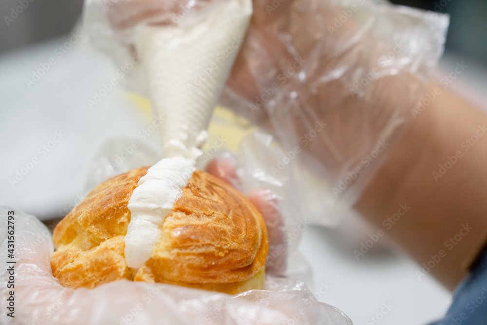 Insert piping tip into each cream Choux Cream puff with cream in a ...