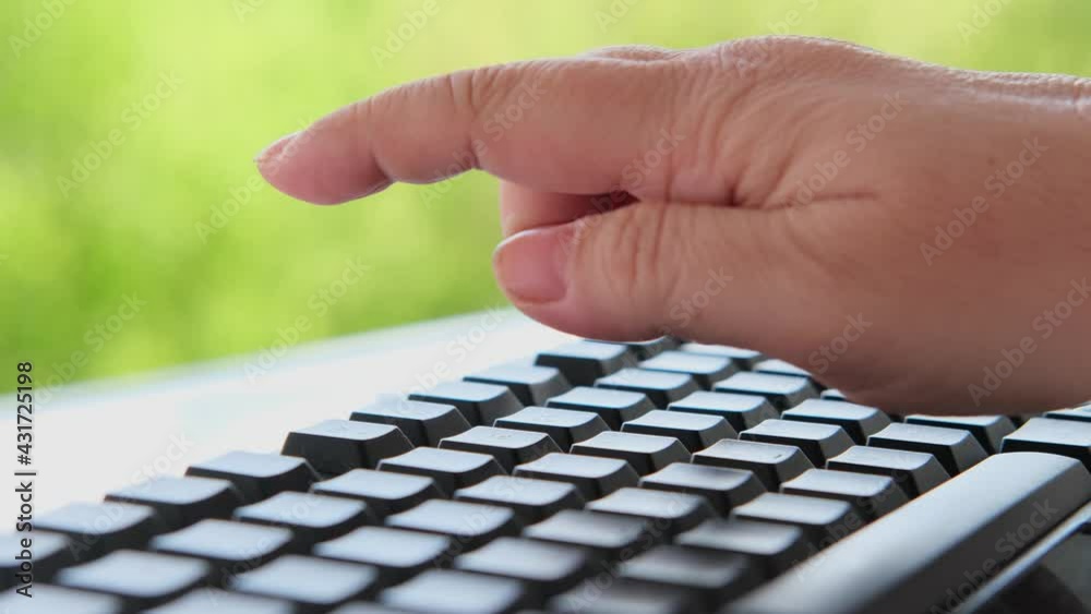 female hand with wrinkles close-up type text on a computer keyboard on ...