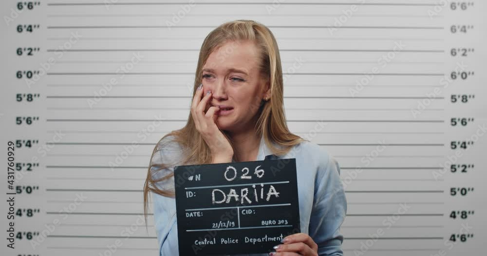 Mugshot of arrested young woman crying while holding sign for photo in ...