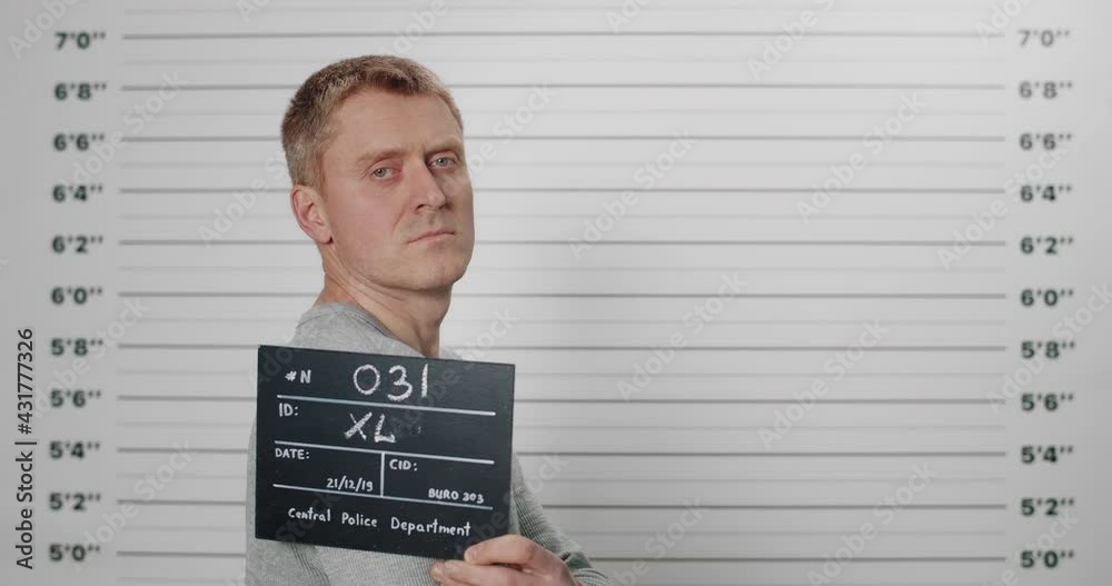 Vidéo Stock Side profile mugshot of man holding sign while being ...