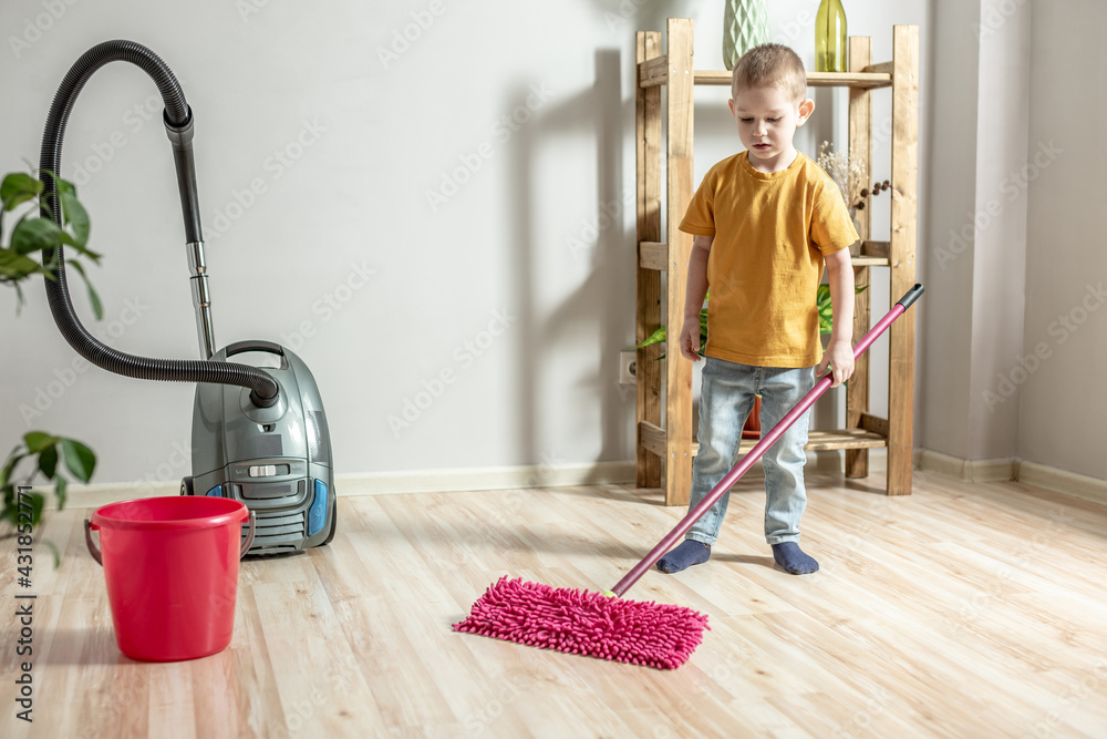Little boy is cleaning the floor of a room using a mop. Concept of ...