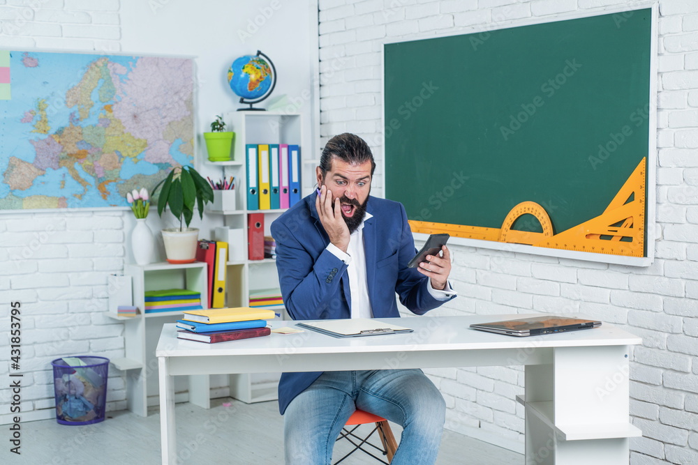 confused man with beard calculating on calculator in school math lesson ...