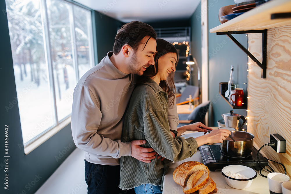Man hugging woman from behind while she is cooking on a high kitchen ...