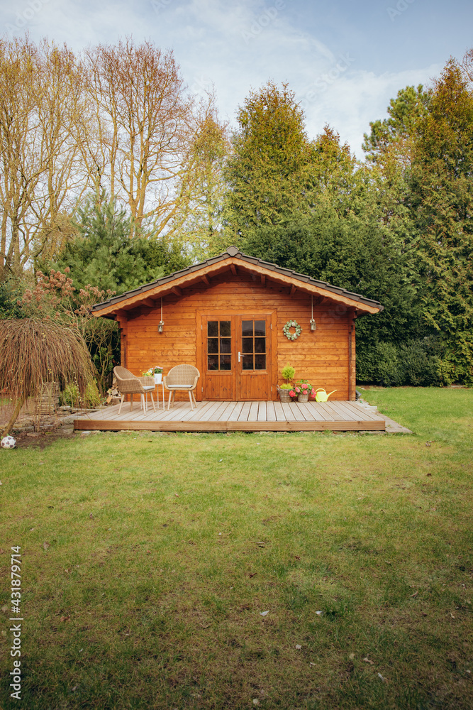 Small wooden hut in the garden. Garden shed with a chair in front of ...