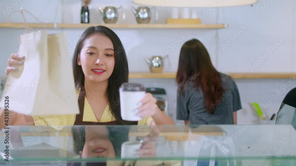Attractive asian female cafe worker giving takeaway food bag to ... Attractive asian female cafe worker giving takeaway food bag to ...