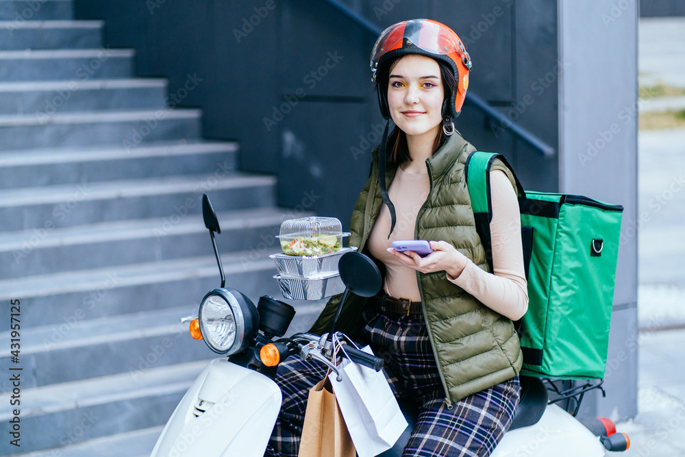 Young female courier in red helmet delivering food on a scooter ...