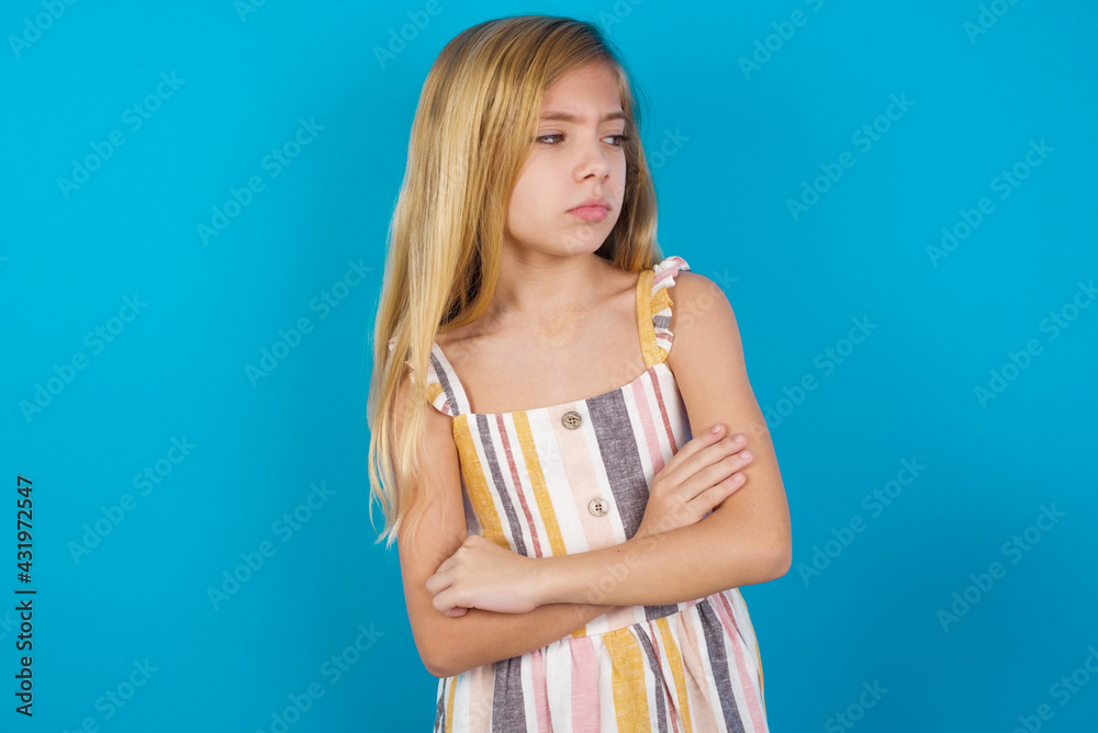 Displeased beautiful Caucasian little girl wearing stripped dress over ...