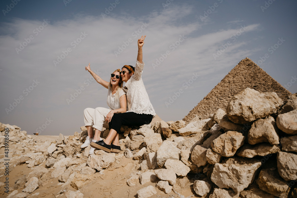 Egypt, Cairo, Two female tourists sitting together on rocks with Great ...