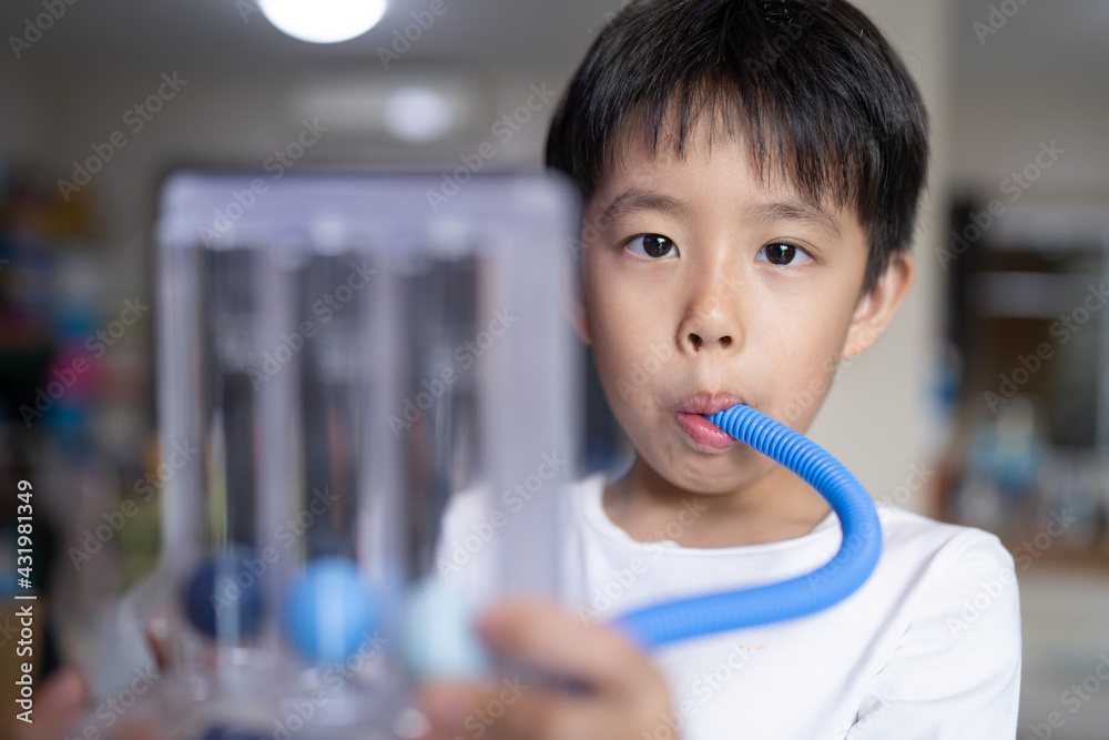 Thin boy uses a Tri-ball Incentive Spirometer for check his lung ...