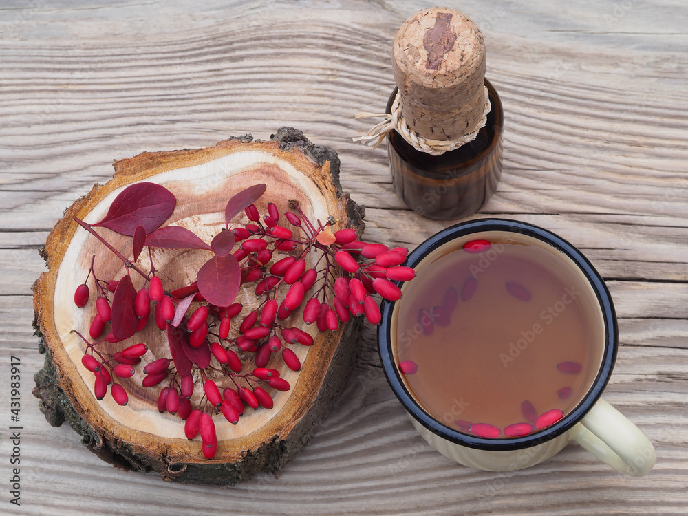 Berries and leaves of the useful berberis plant and a tea in a mug ...