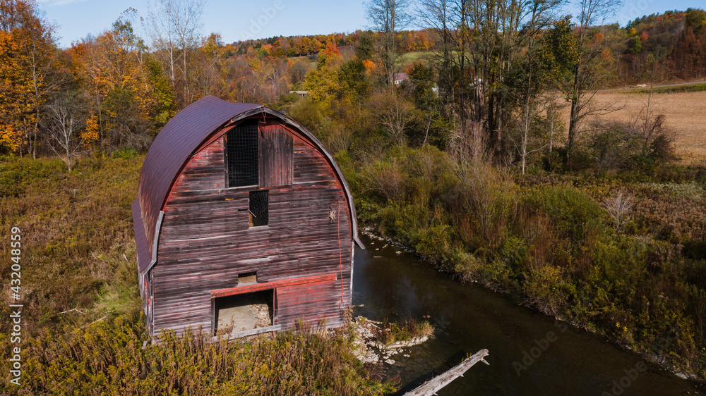 Abandoned Antique Red Barn with Rounded Roof Overhanging Creek Bank ...
