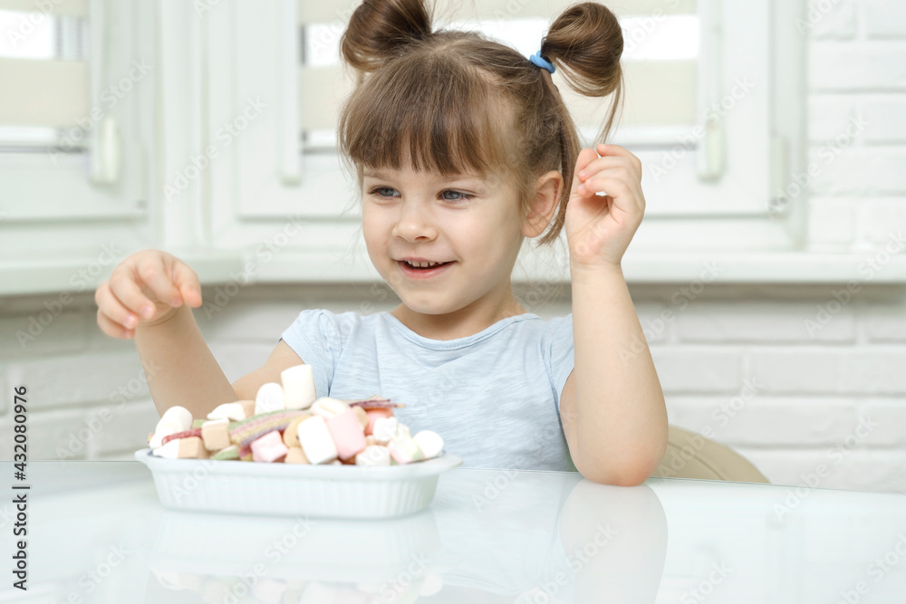 happy contented little girl eating candy from a plate full of sweets ...