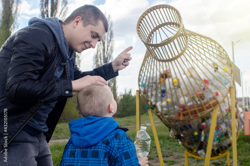 Dad and son throw the plastic bottle into the plastic collection ...