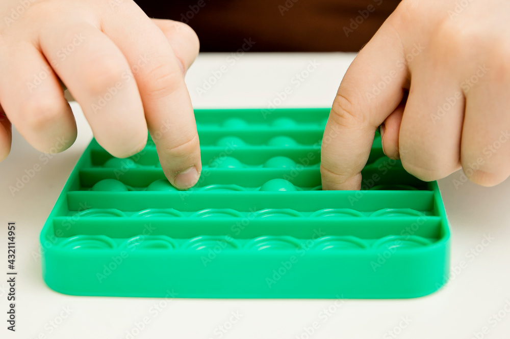 Close up shot of kids fingers on pop it fidget toy. Instrument for ...