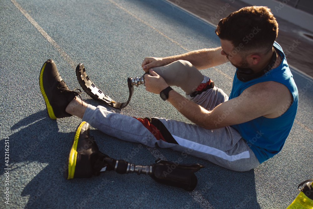 Caucasian male athlete fixing his prosthetic leg while sitting on ...