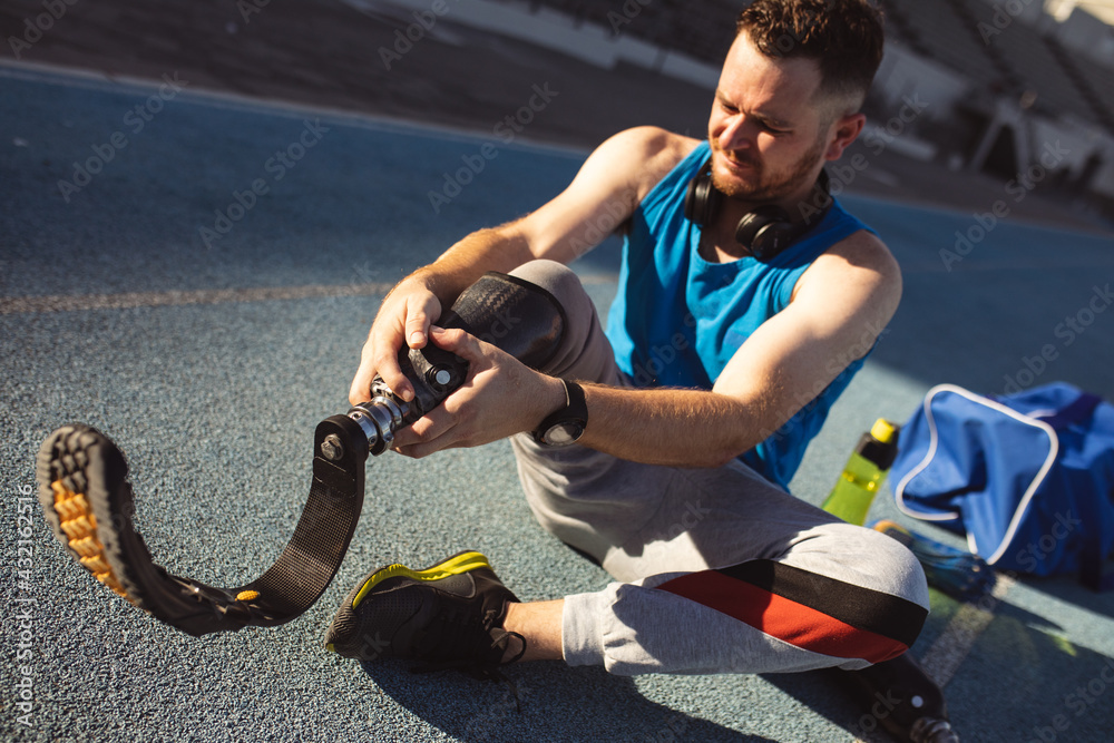 Foto de Caucasian male athlete fixing his prosthetic leg while sitting ...