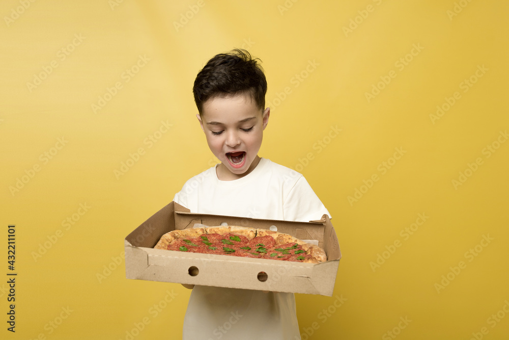 Brunet child posing with pizza in delivery box isolated on yellow ...