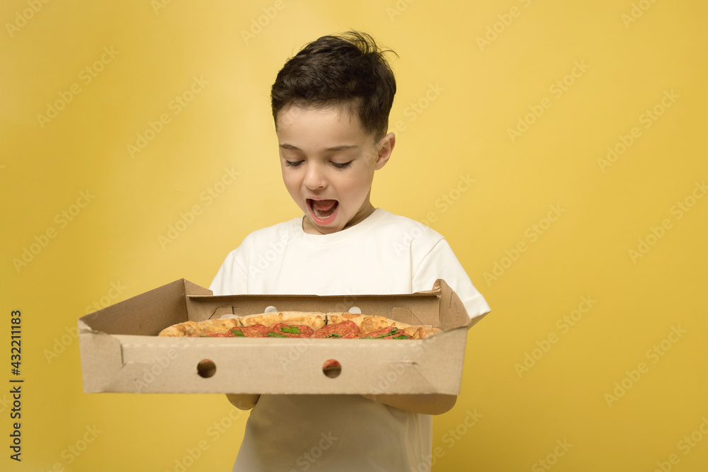 Brunet child posing with pizza in delivery box isolated on yellow ...