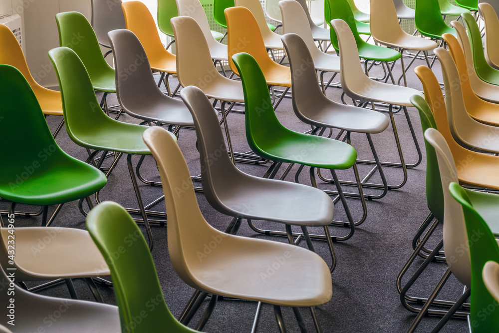 Rows of seats in assembly hall. Colored plastic chairs on gray floor ...