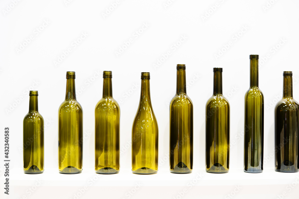 Glass bottles of different shapes and sizes stand in a row on a gray ...