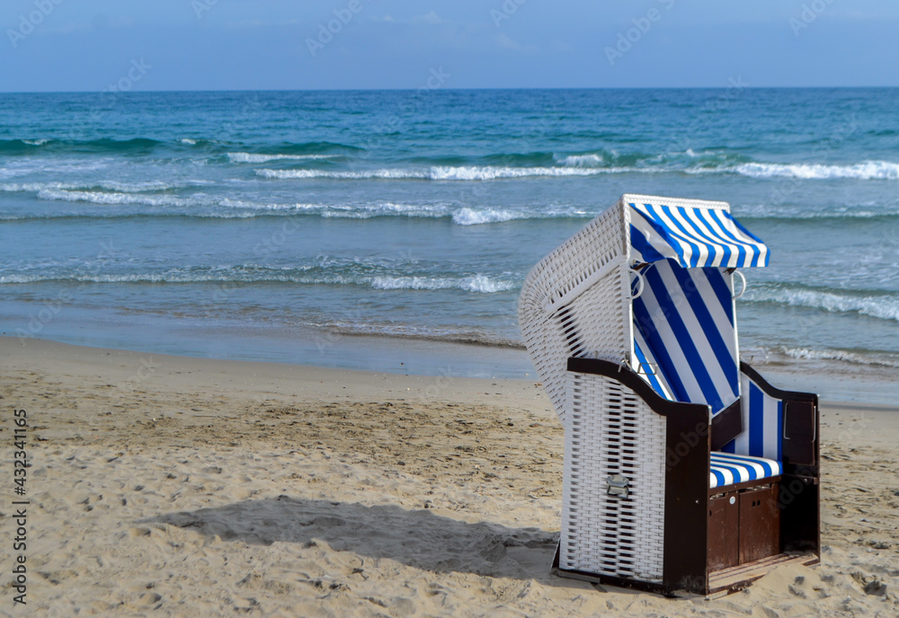 Roofed wicker beach chair on beach with a view of the waves of the ...
