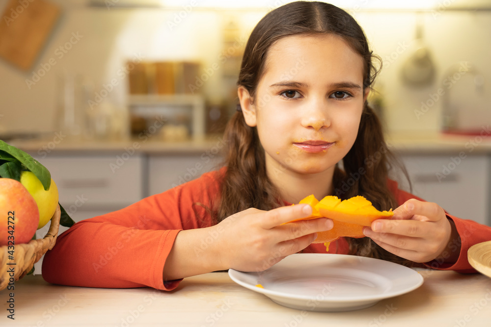 Cute child girl is happy to eat mangoes. Schoolgirl joy tasty eating ...
