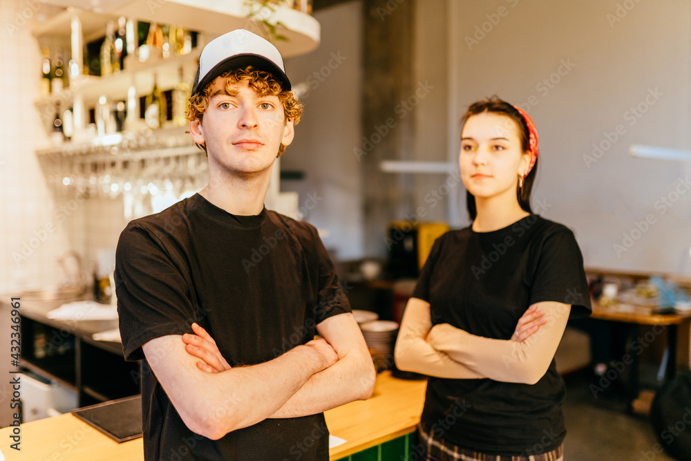 Diverse waiter and waitress looking at camera, curly red haired male ...