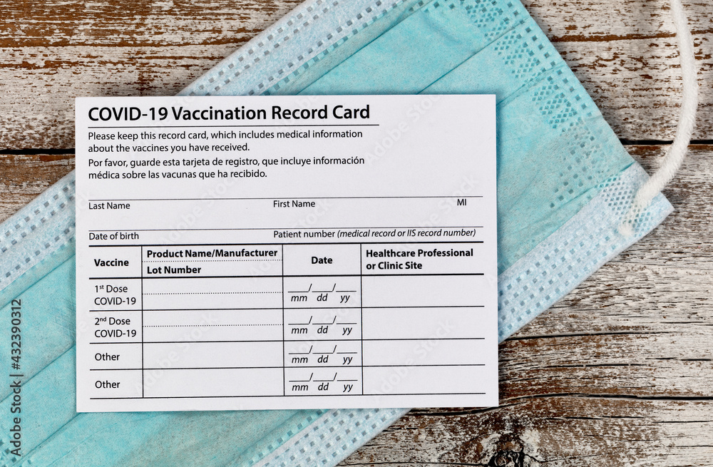 Covid 19 vaccination record card with facemask in close up view ...