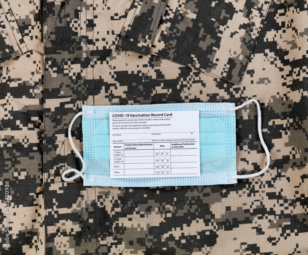 Covid 19 vaccination record card and personal facemask on military ...